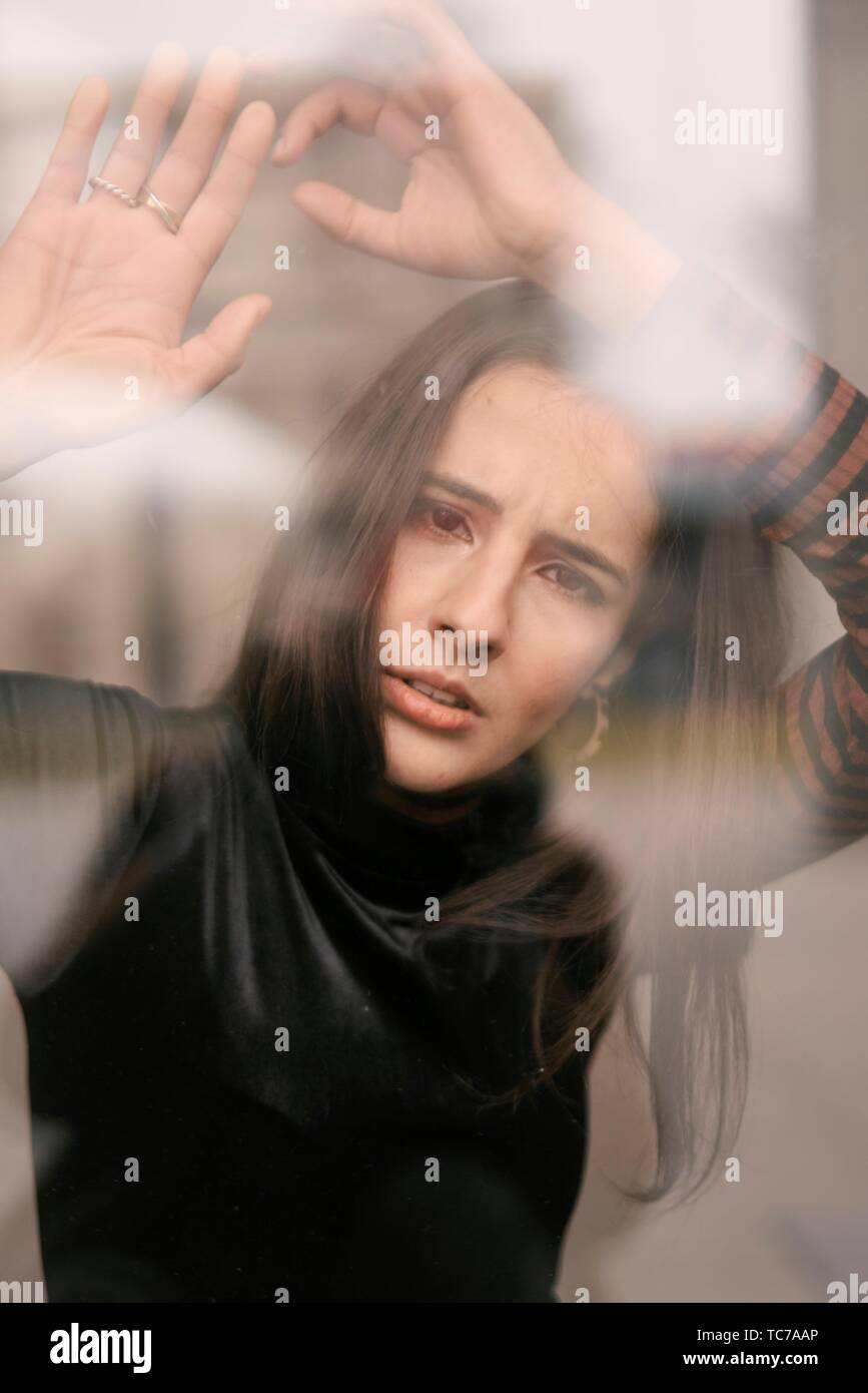 portrait of lonely emotional woman behind glass window, abandoned ...