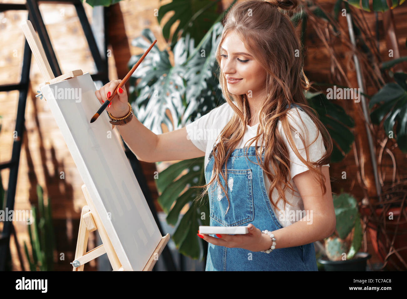 Pretty talented female painter painting on easel Stock Photo - Alamy