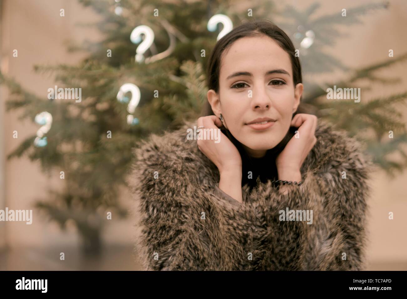 confident woman in front Christmas tree with lights of question marks ...