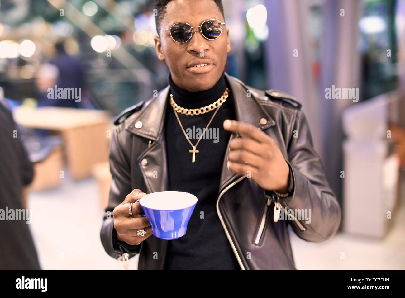 young fancy man holding coffee cup and gesticulating, African descent ...