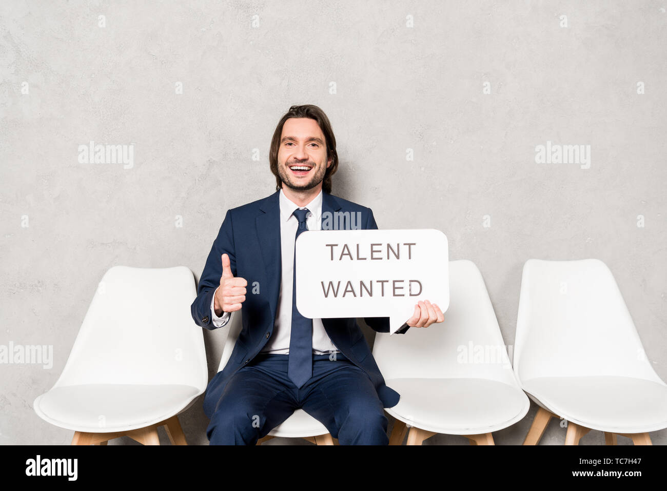 happy recruiter sitting on chair and holding speech bubble with talent ...