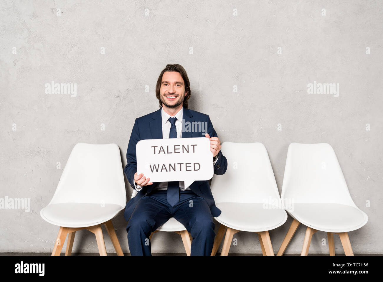 happy recruiter sitting on chair and holding speech bubble with talent ...