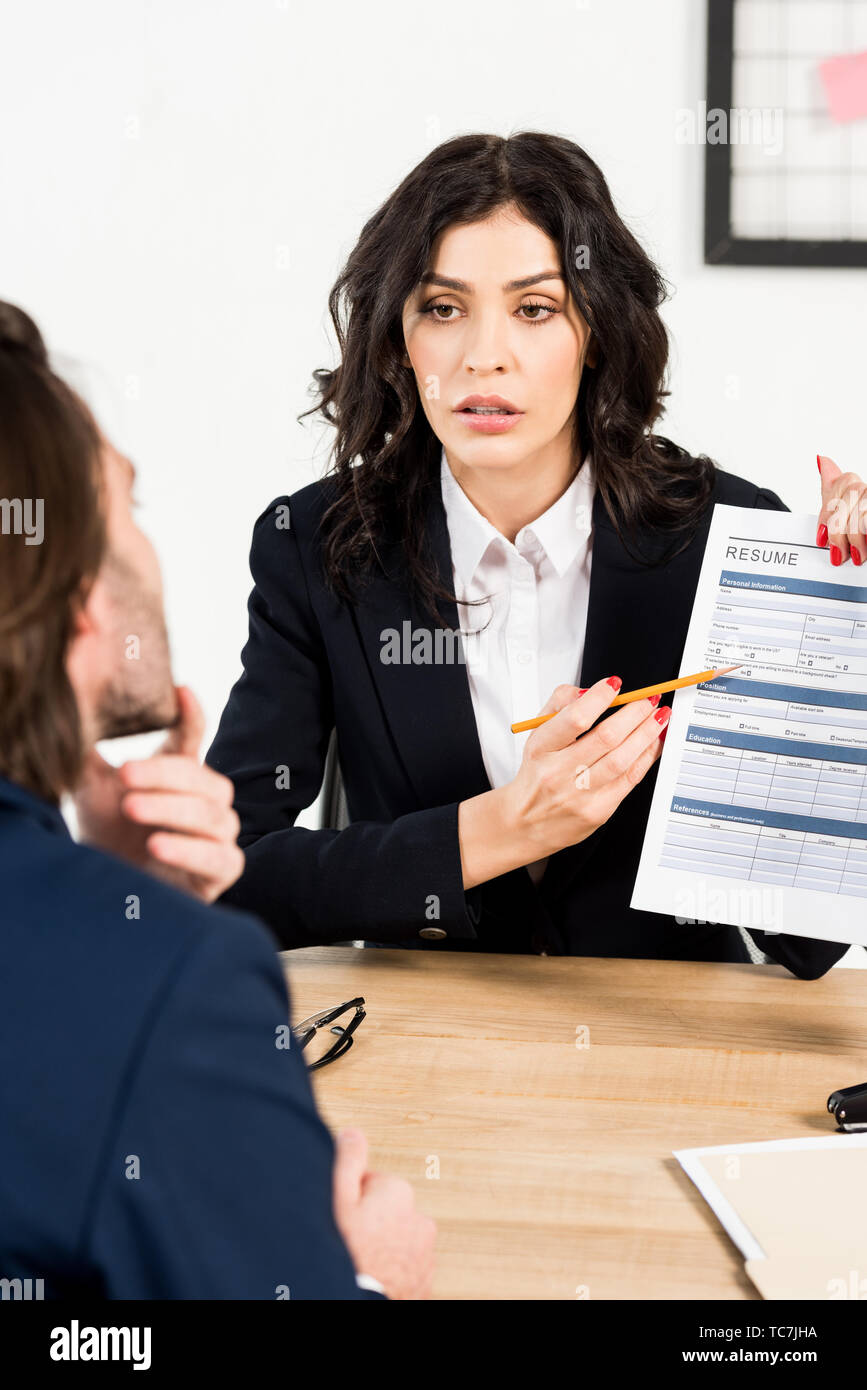 selective focus of attractive recruiter holding resume near man during ...