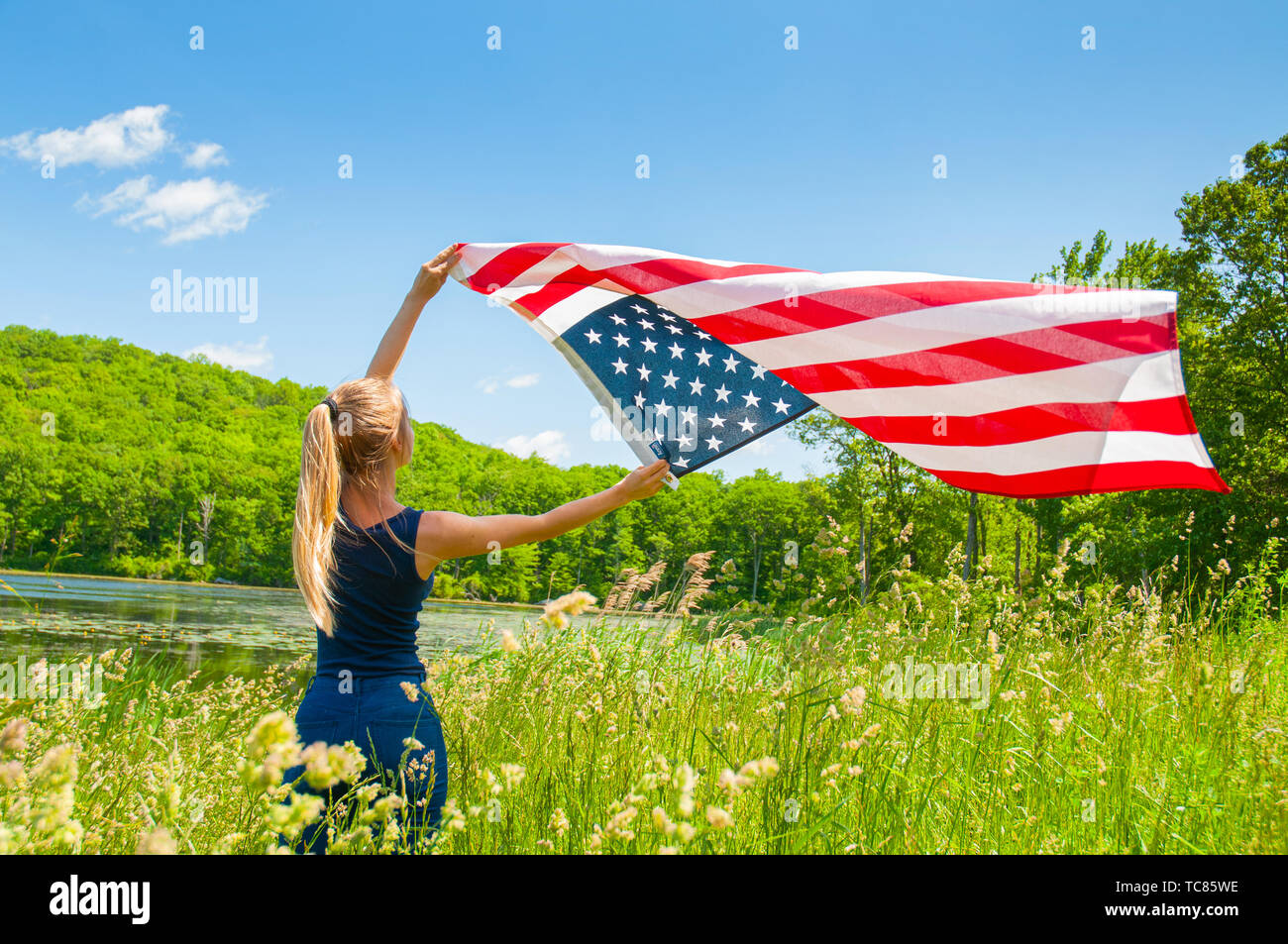 United States flag . Young woman holding American flag outdoors ...