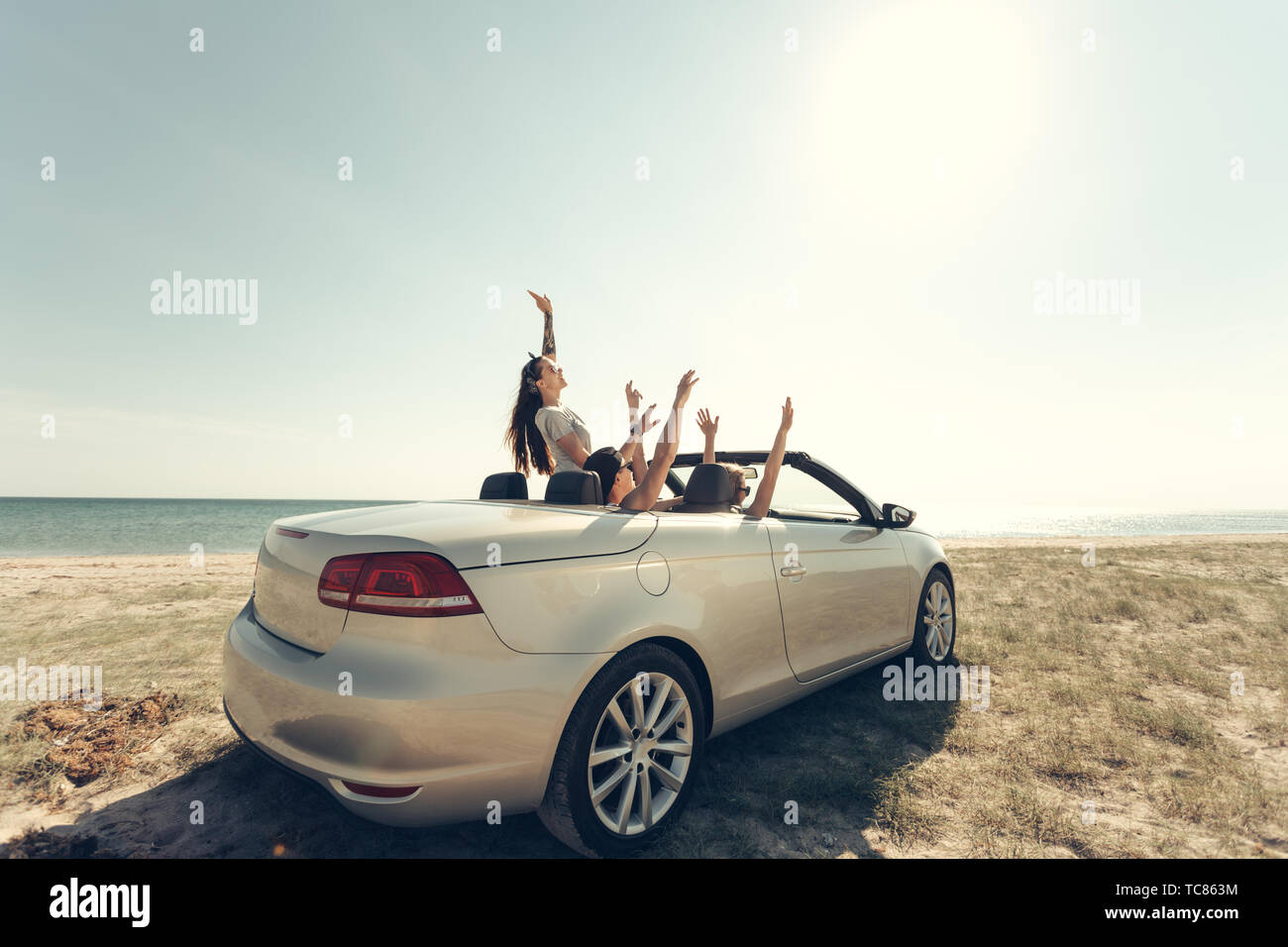 Smiling friends driving car near the sea and having fun Stock Photo - Alamy