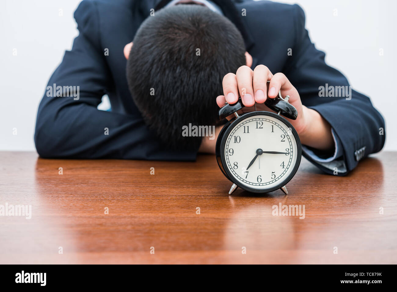 A tired young man holds the alarm clock Stock Photo - Alamy