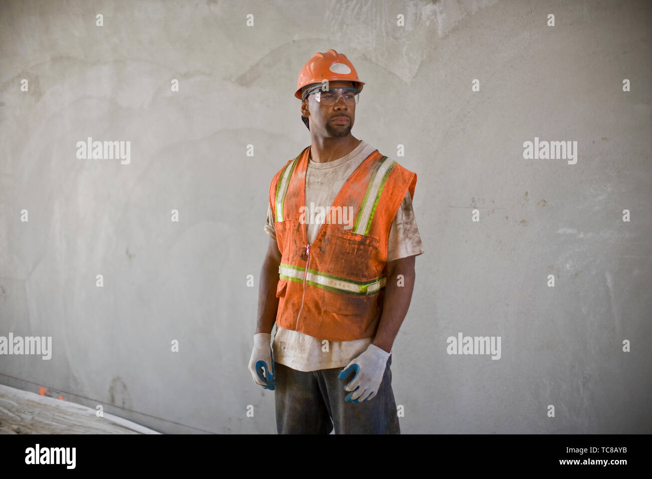 Dirty mid-adult construction worker wearing a helmet and hi-visibility ...