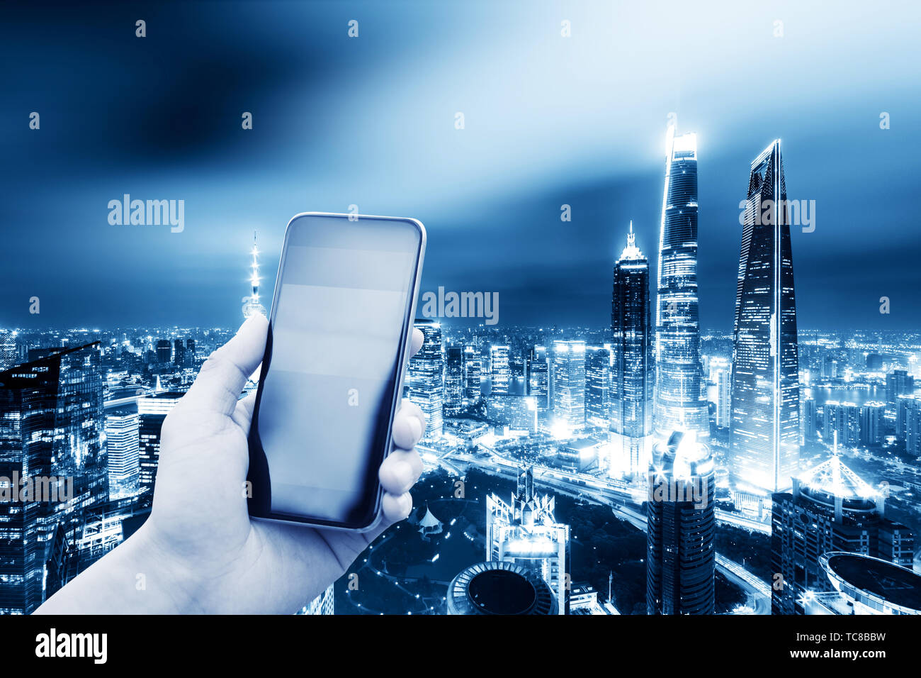 Mobile phone with modern city at night Stock Photo - Alamy