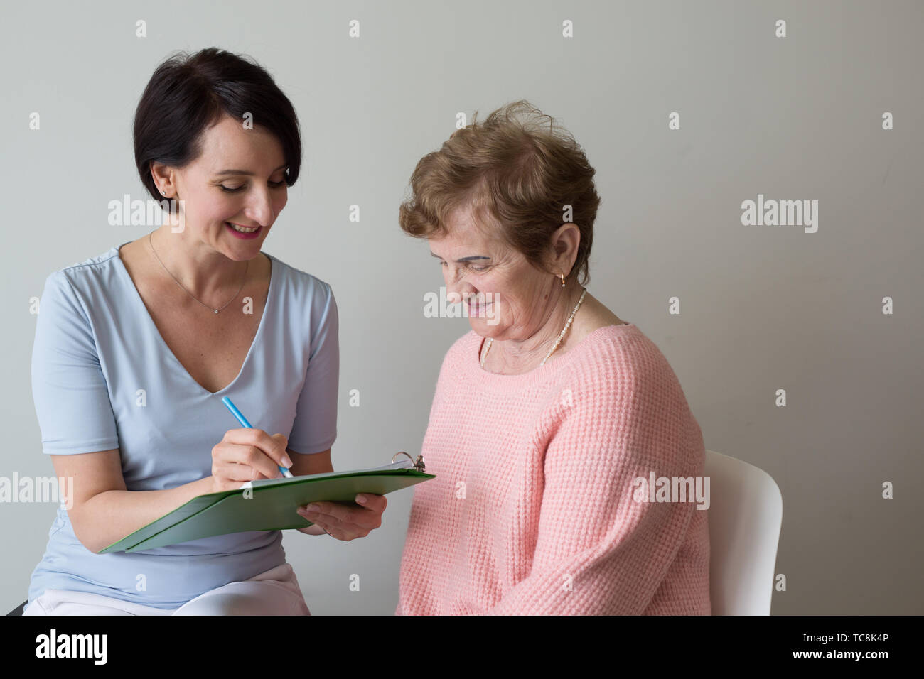 Young woman asking questions elderly female client survey Stock Photo ...