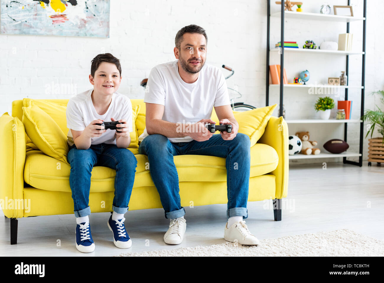 father and son playing Video Game on couch in Living Room Stock Photo ...