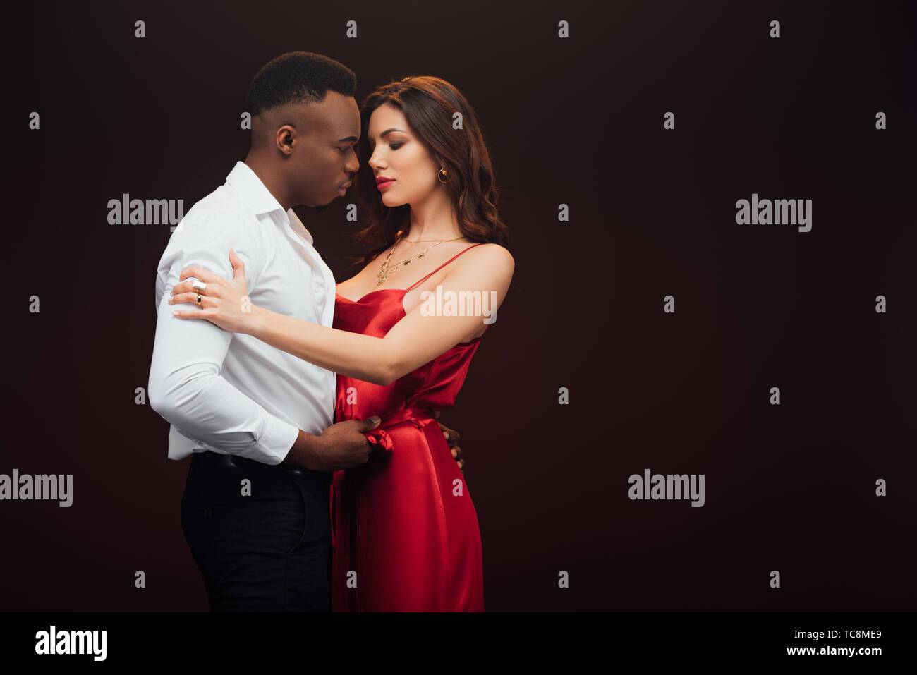 Beautiful Interracial Couple In Formal Wear Embracing Isolated On Black