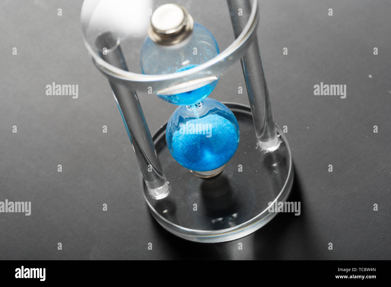 Time is passing. Blue hourglass close up Stock Photo - Alamy