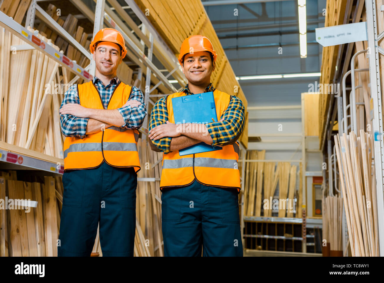 cheerful multicultural workers with crossed arms smiling and looking at ...