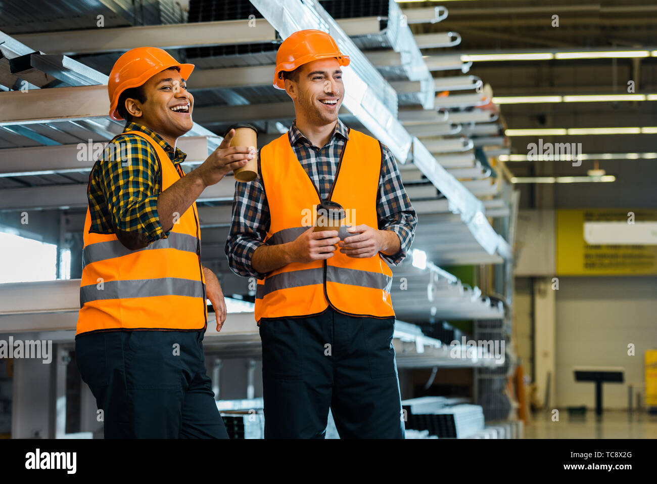 laughing multicultural workers holding paper cups and looking away in ...