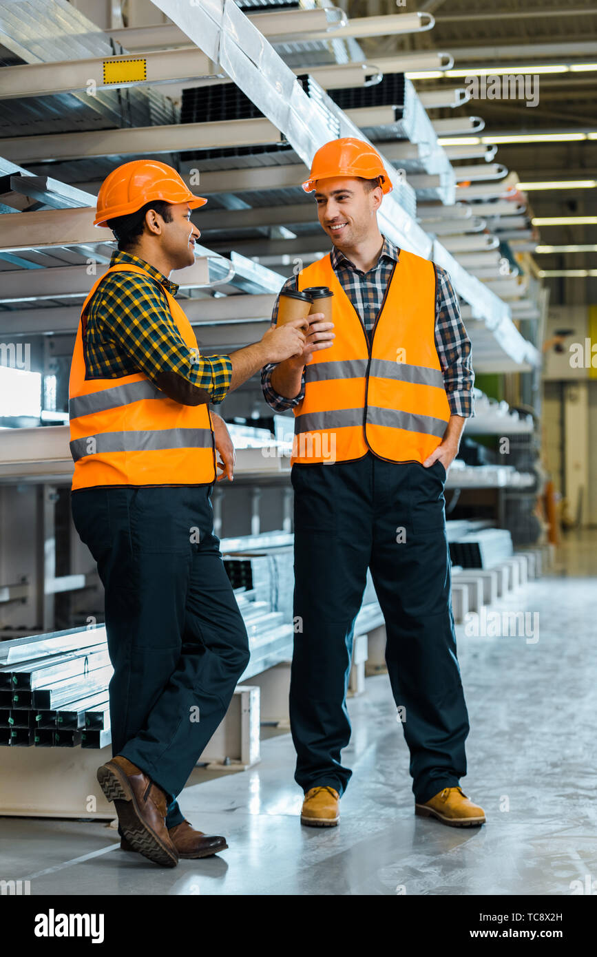 cheerful multicultural workers clinking with paper cups while standing ...
