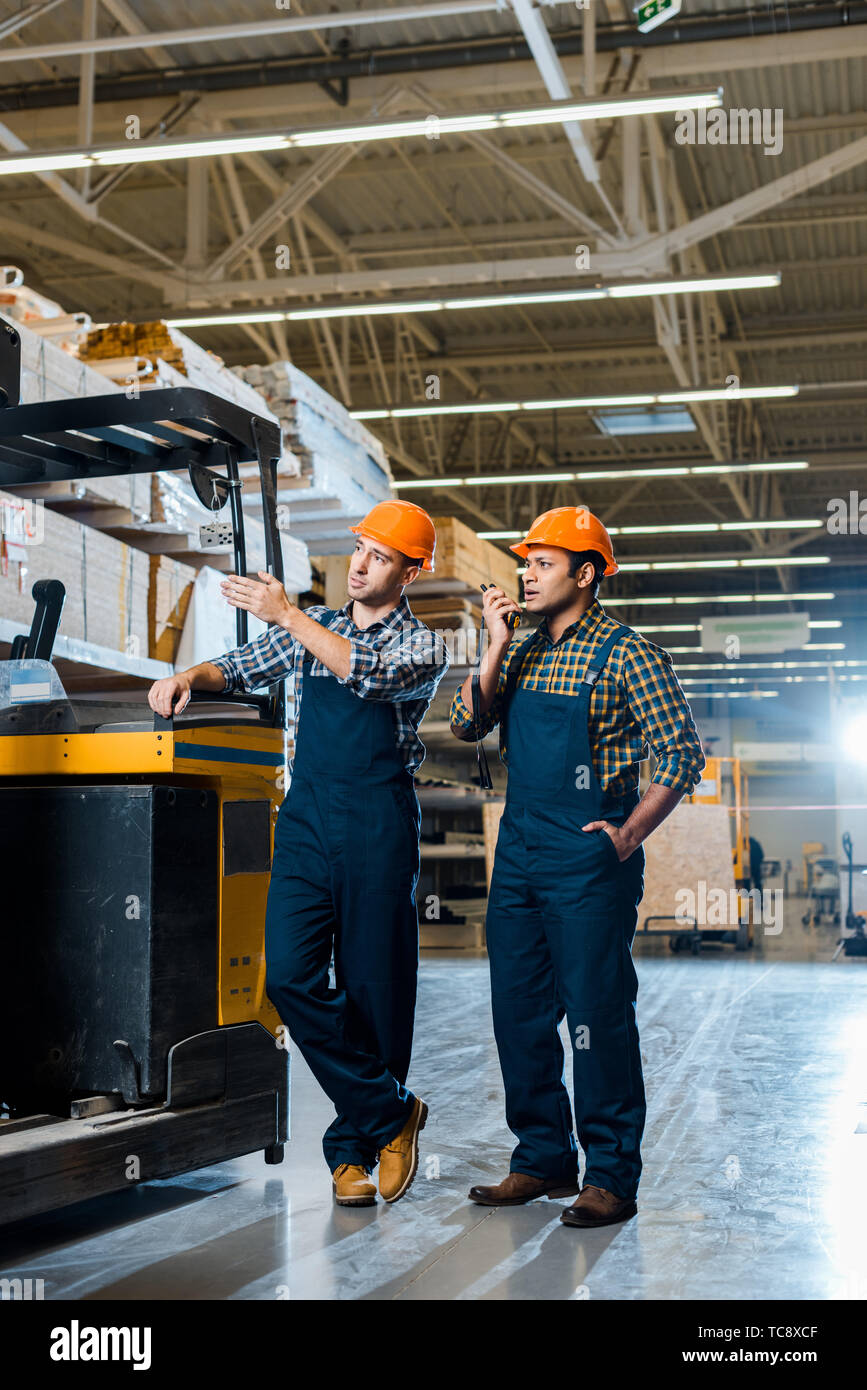 concentrated multicultural workers in helmets and plaid shirts standing ...