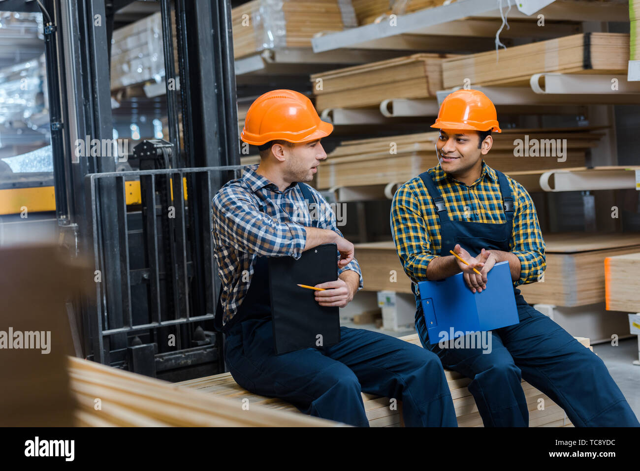 selective focus of two smiling multicultural workers sitting in ...