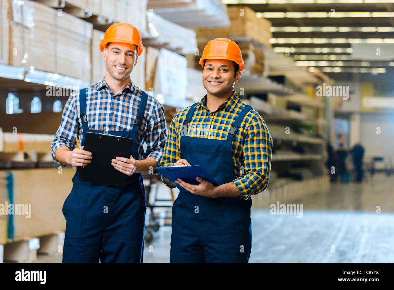 two multicultural workers in uniform smiling and looking at camera in ...