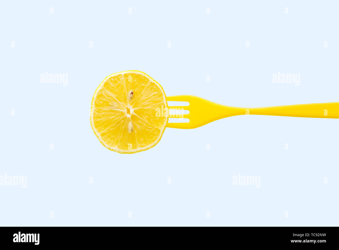 Lemon slice on yellow plastic fork against pastel blue background Stock Photo - Alamy