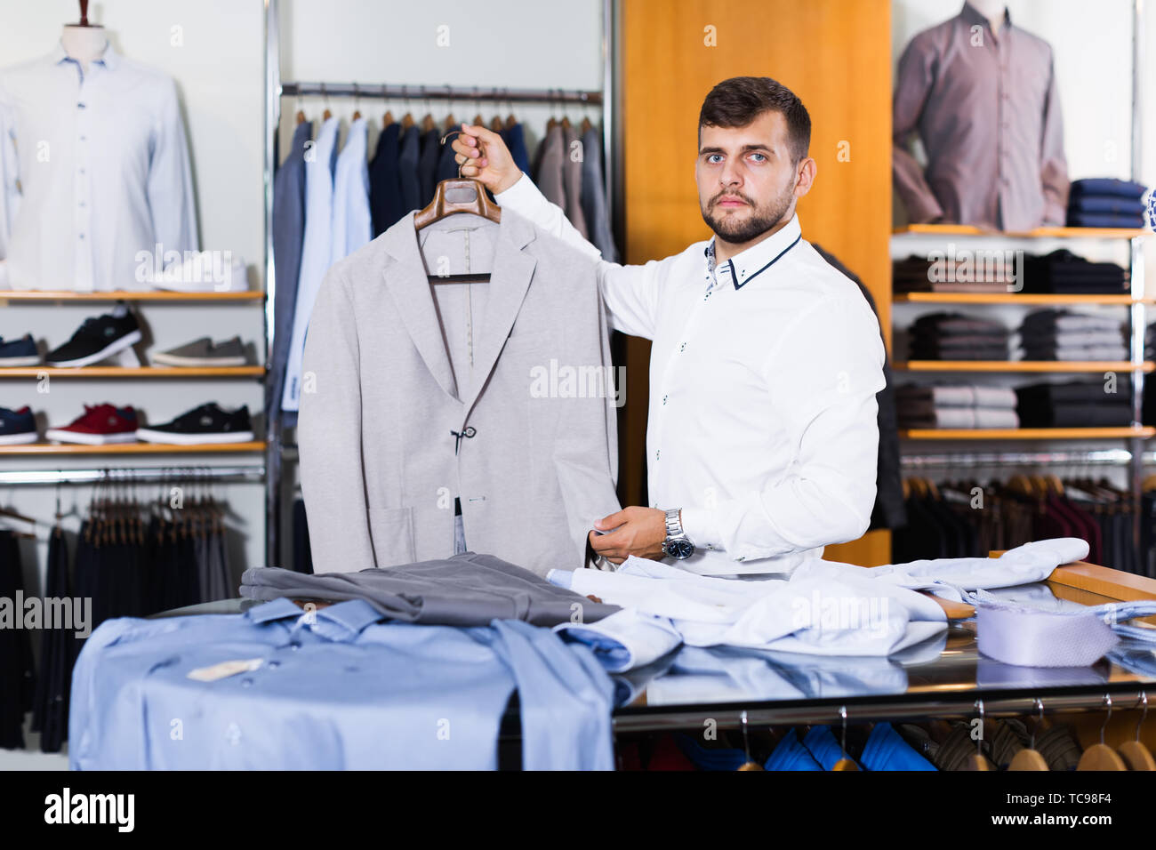 positive male displaying classic jacket in men clothes shop Stock Photo ...