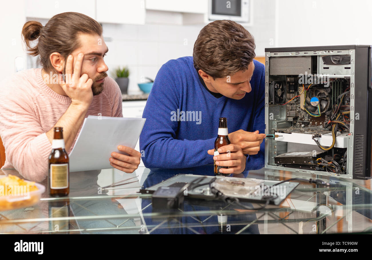 Two men repairing a desktop computer and drink beer Stock Photo - Alamy