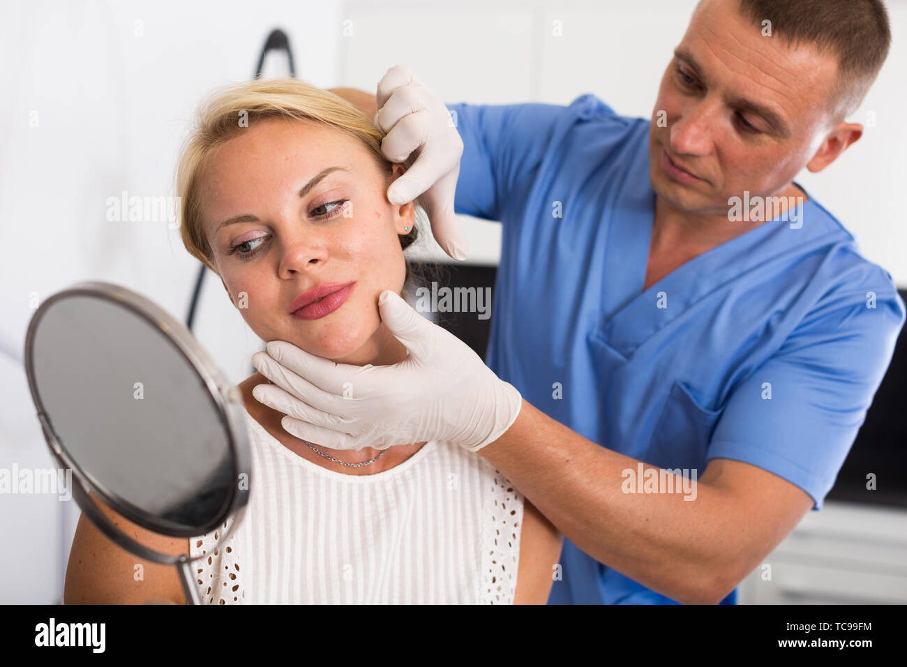 Doctor is examining woman patient behind mirror before the procedure in ...