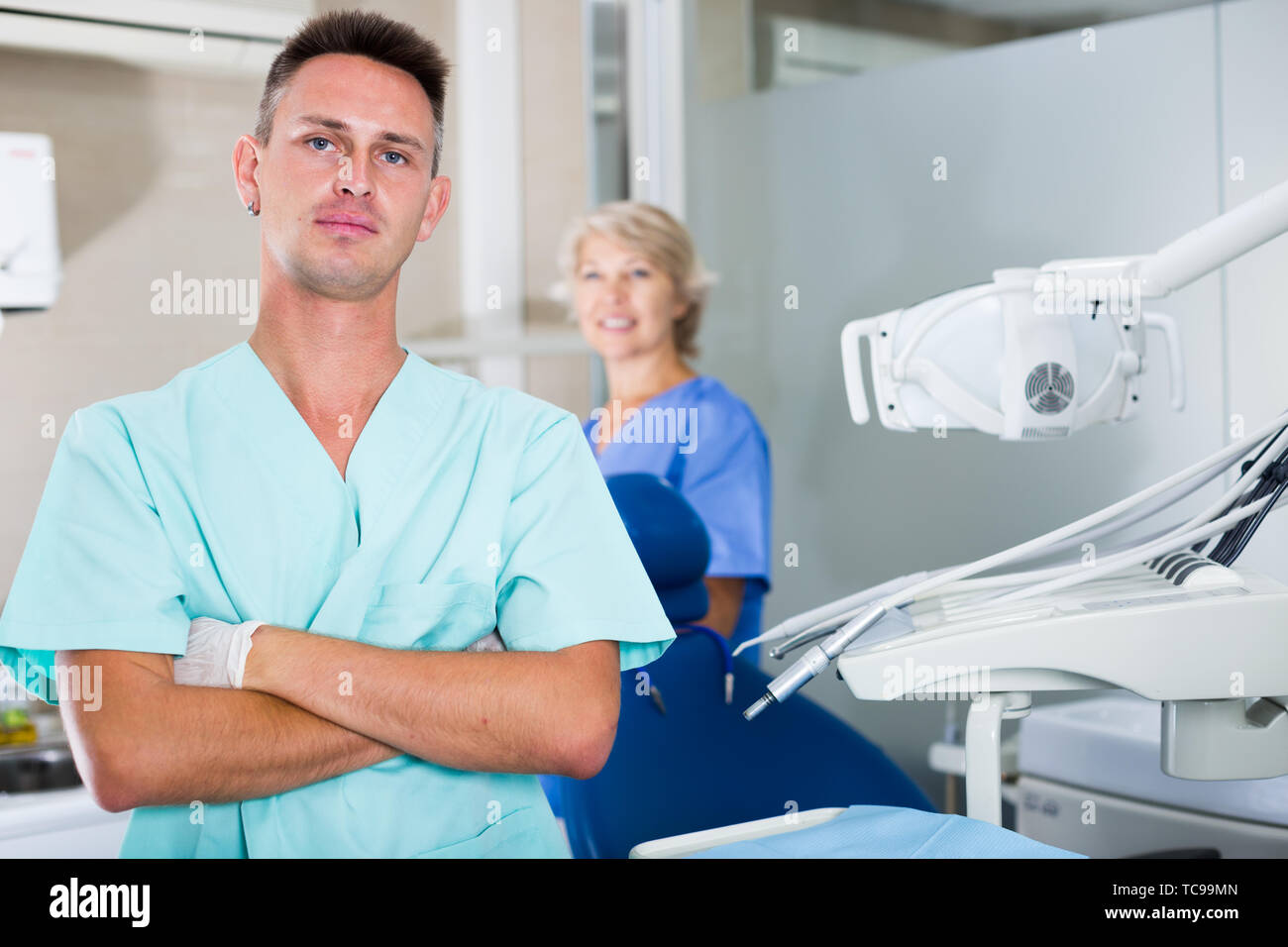 Portrait of professional male dentist with arms crossed with dental ...