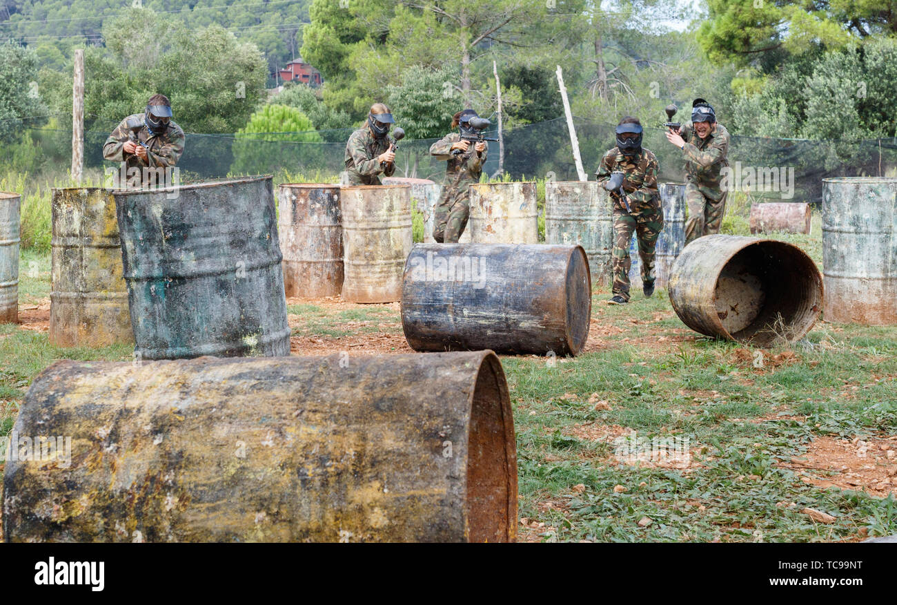 Team of cheerful positive people playing paintball on battlefield ...