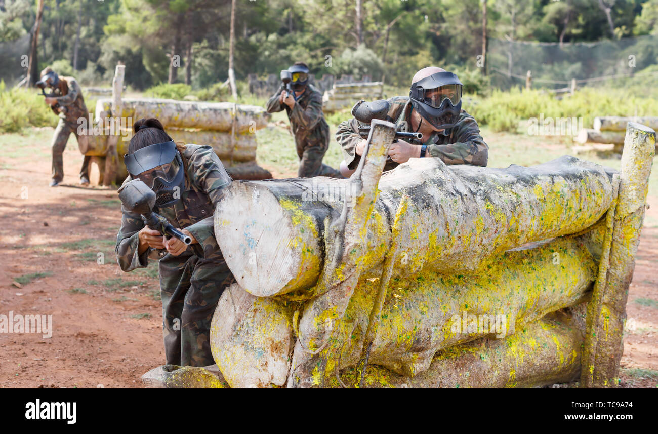 Paintball players aiming and shooting with a marker guns at the ...