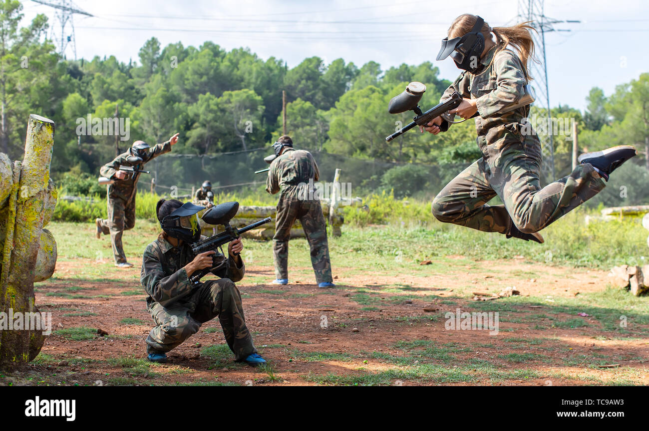 Dynamic paintball battle. Portrait female player jumping and aiming ...