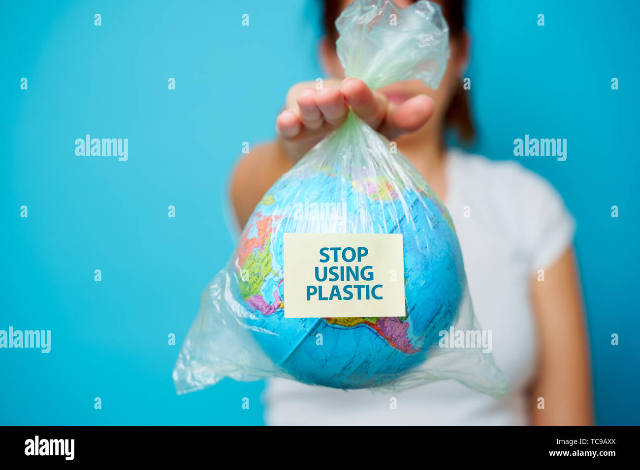 Woman holds in hands plastic bag with sticker text STOP USING PLASTIC ...