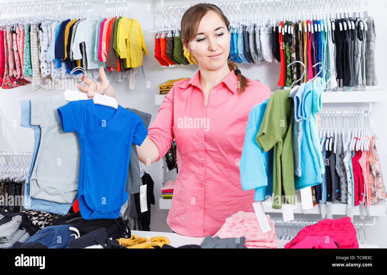 Happy cheerful smiling female is shopping and looking on clothes in the ...