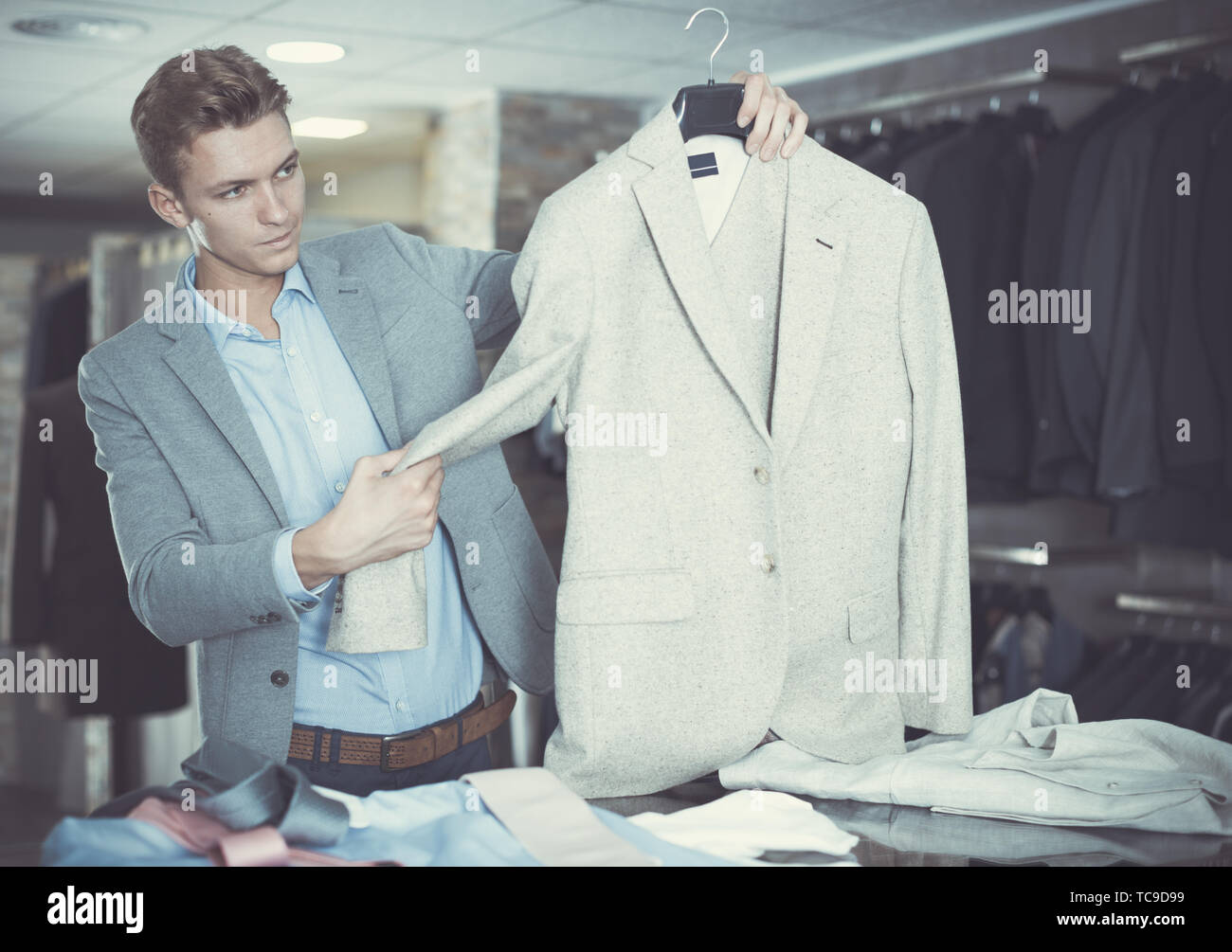 Man in business clothes seller holding jacket in the dress shop Stock ...