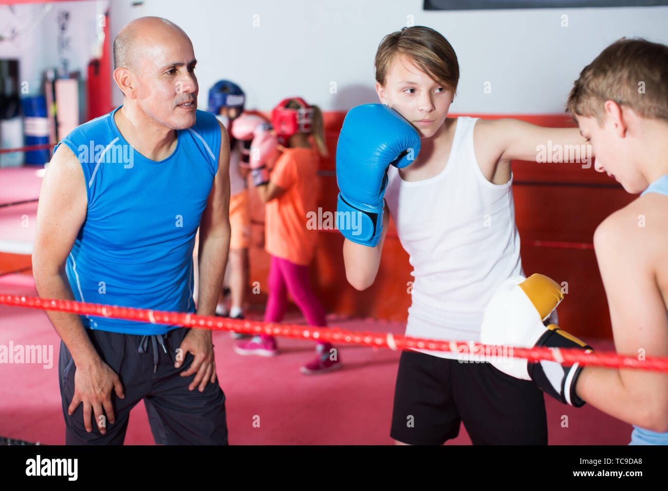 Portrait of active teenage boxer sparring on the ring in boxing hall ...