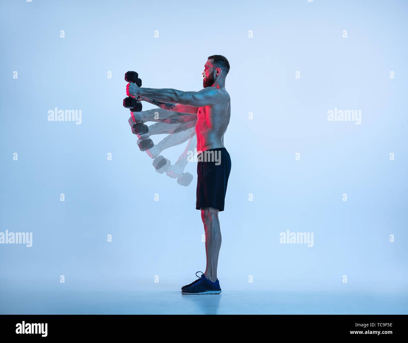 Balance. Young caucasian bodybuilder training over blue background in ...