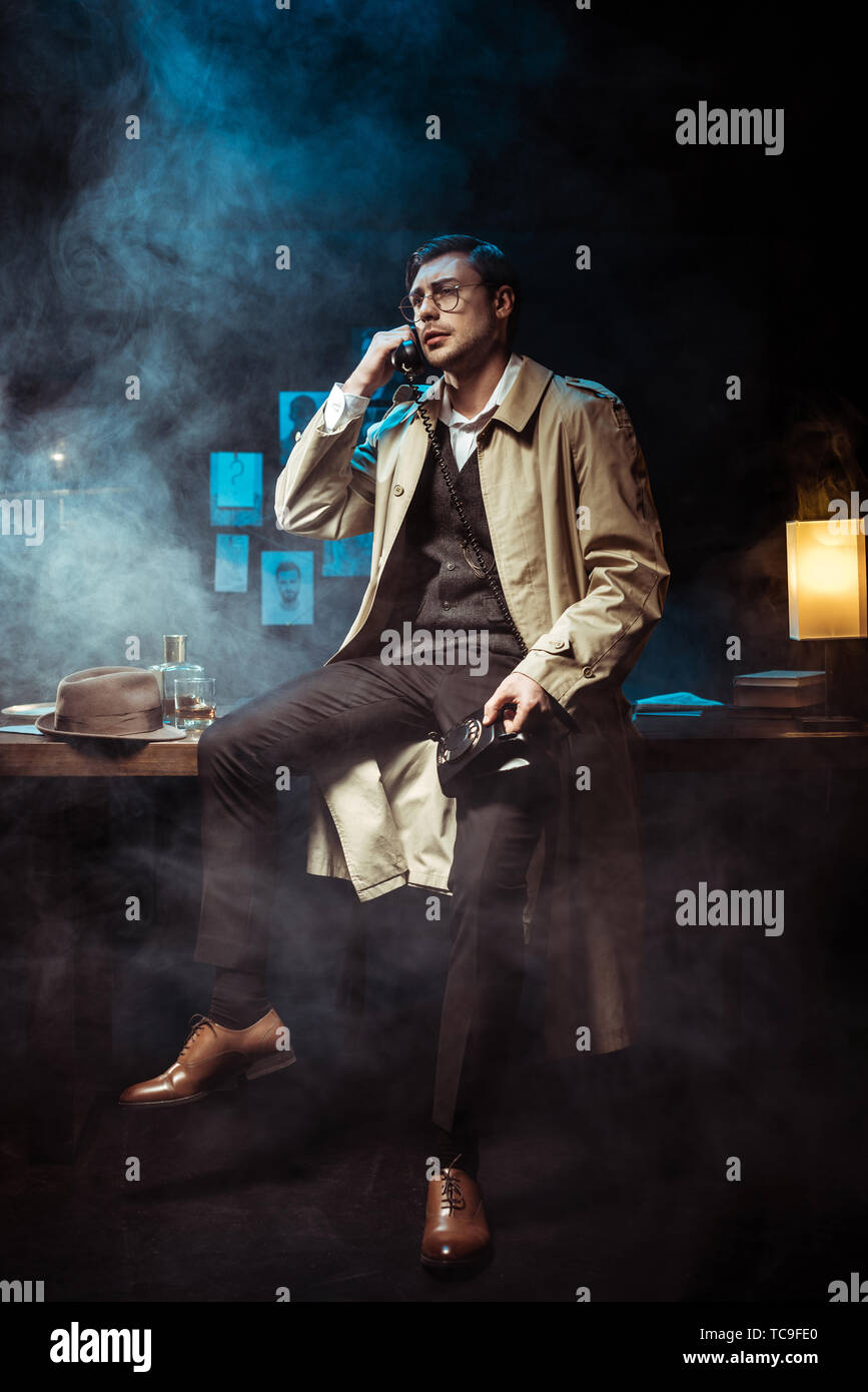 Detective in glasses sitting on table and talking on telephone Stock ...