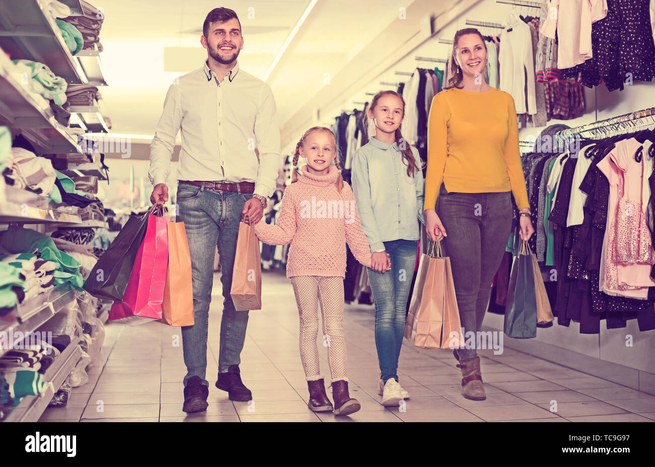 Happy family with two daughters walking in store after shopping Stock ...