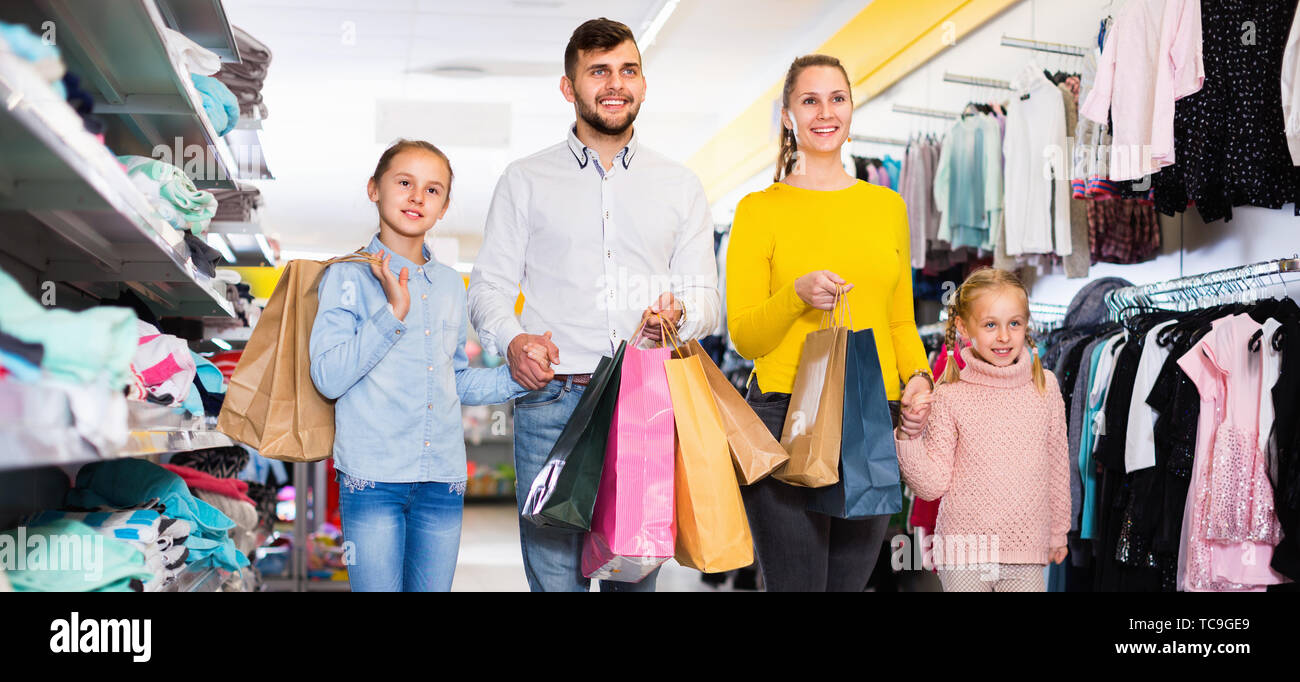Young cheerful positive smiling parents with two little girls shopping ...