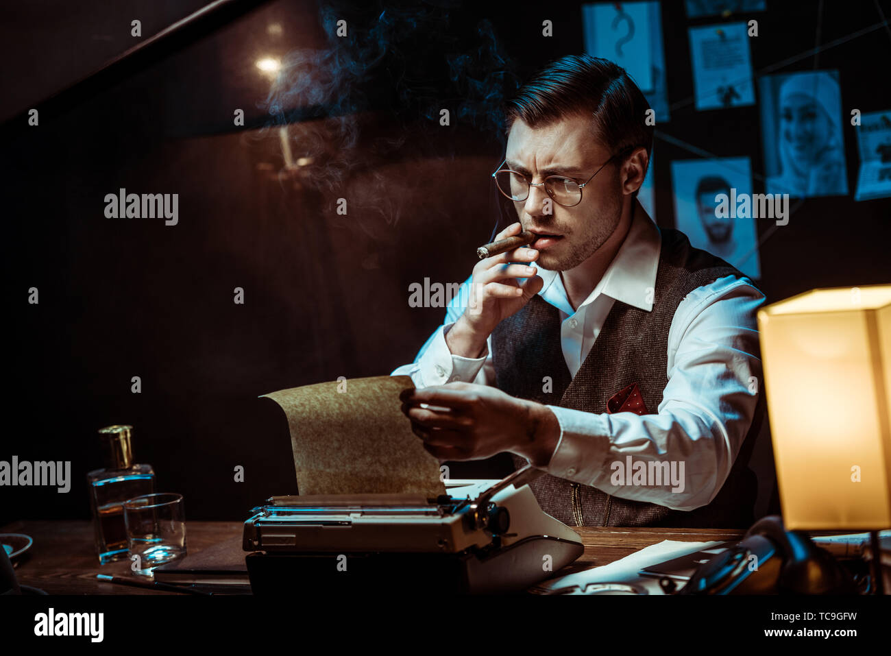 Detective in glasses smoking cigar while using typewriter in dark ...
