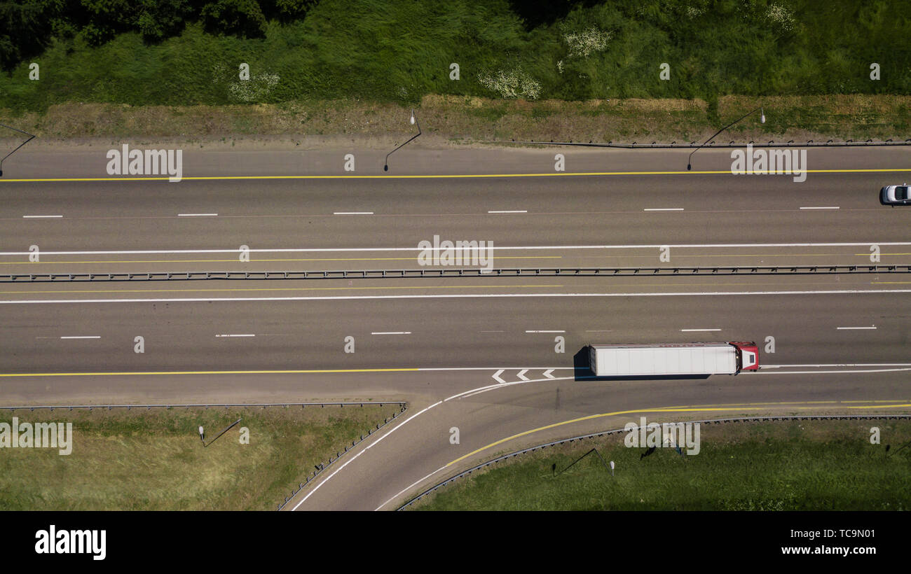 Top down close up of highway traffic with semi truck, white arrow signs ...