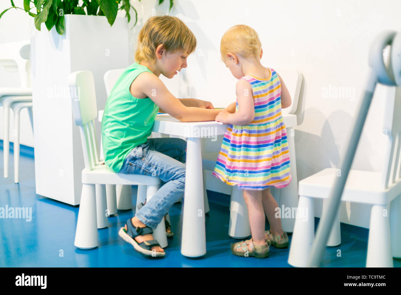 Kids playing and drawing in kids table, activity corner Stock Photo - Alamy