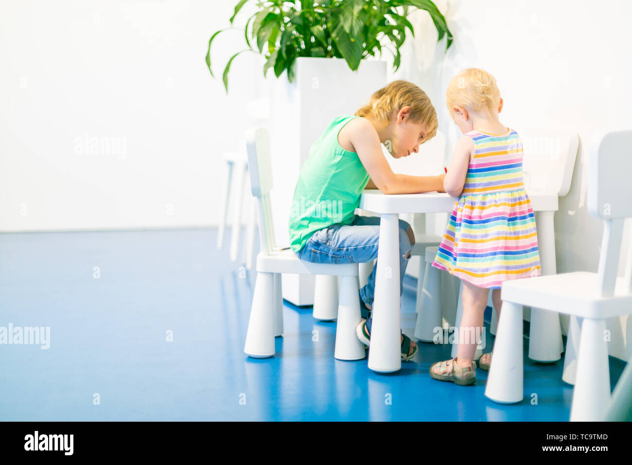 Kids playing and drawing in kids table, activity corner Stock Photo - Alamy