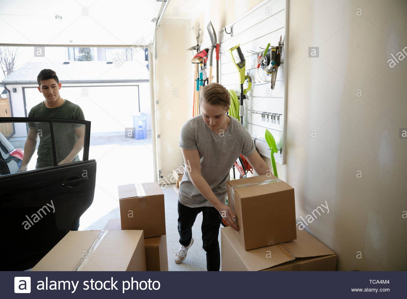 Teenage couple loading cardboard boxes into car Stock Photo - Alamy