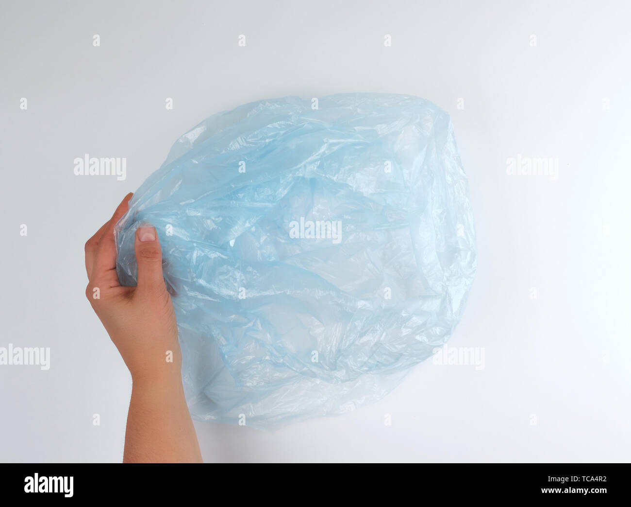 blue plastic garbage bag in female hand on a white background, top view ...