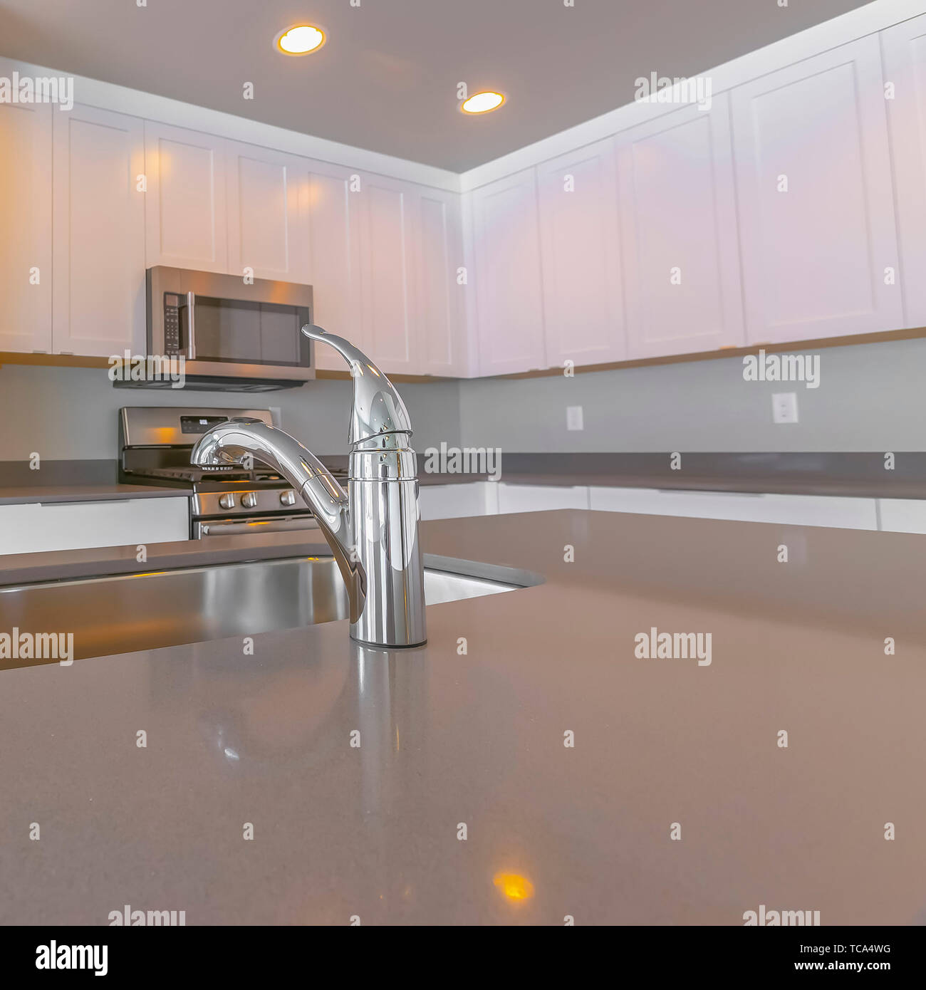 Square Modern kitchen of a new home with close up on the shiny faucet ...