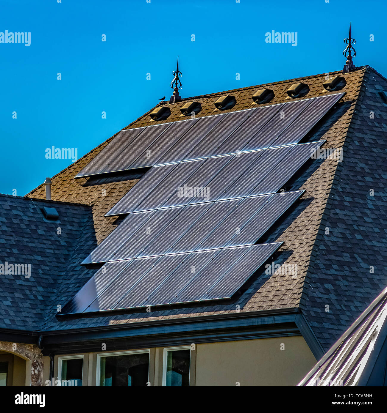 Square Solar panels on the dark gray roof with blue sky background on a ...