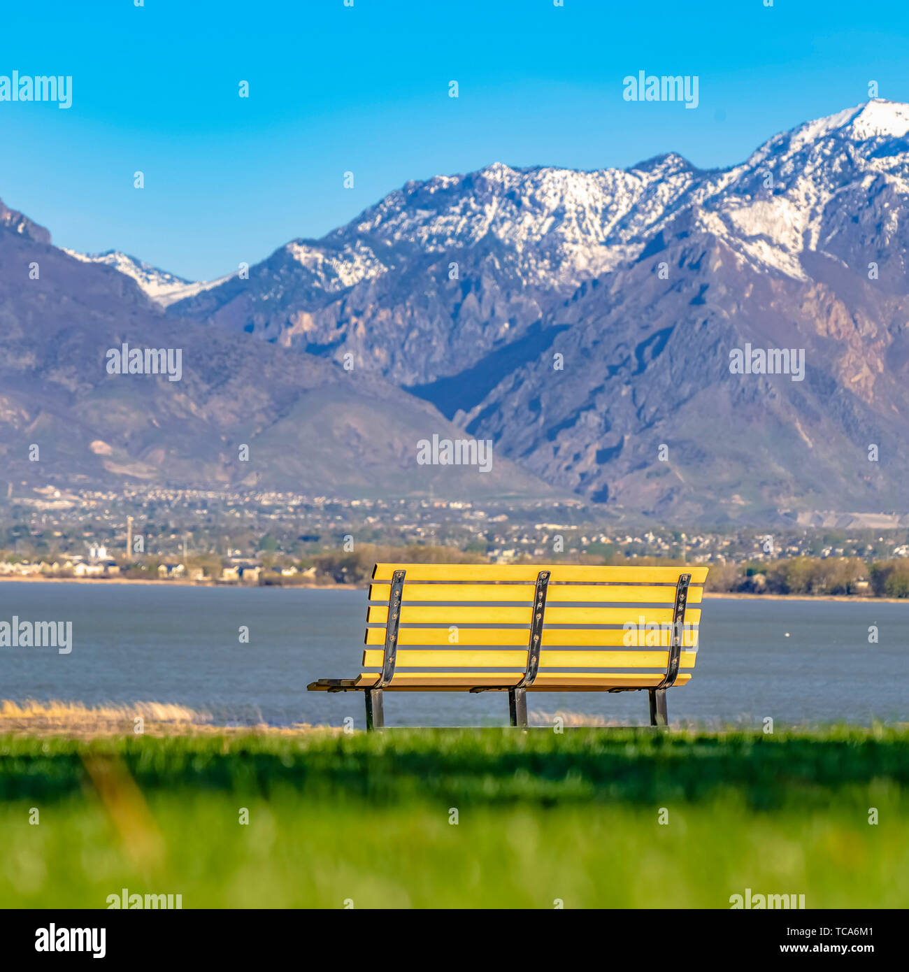 Square Empty bench facing an amazing view of a lake and mountain capped ...