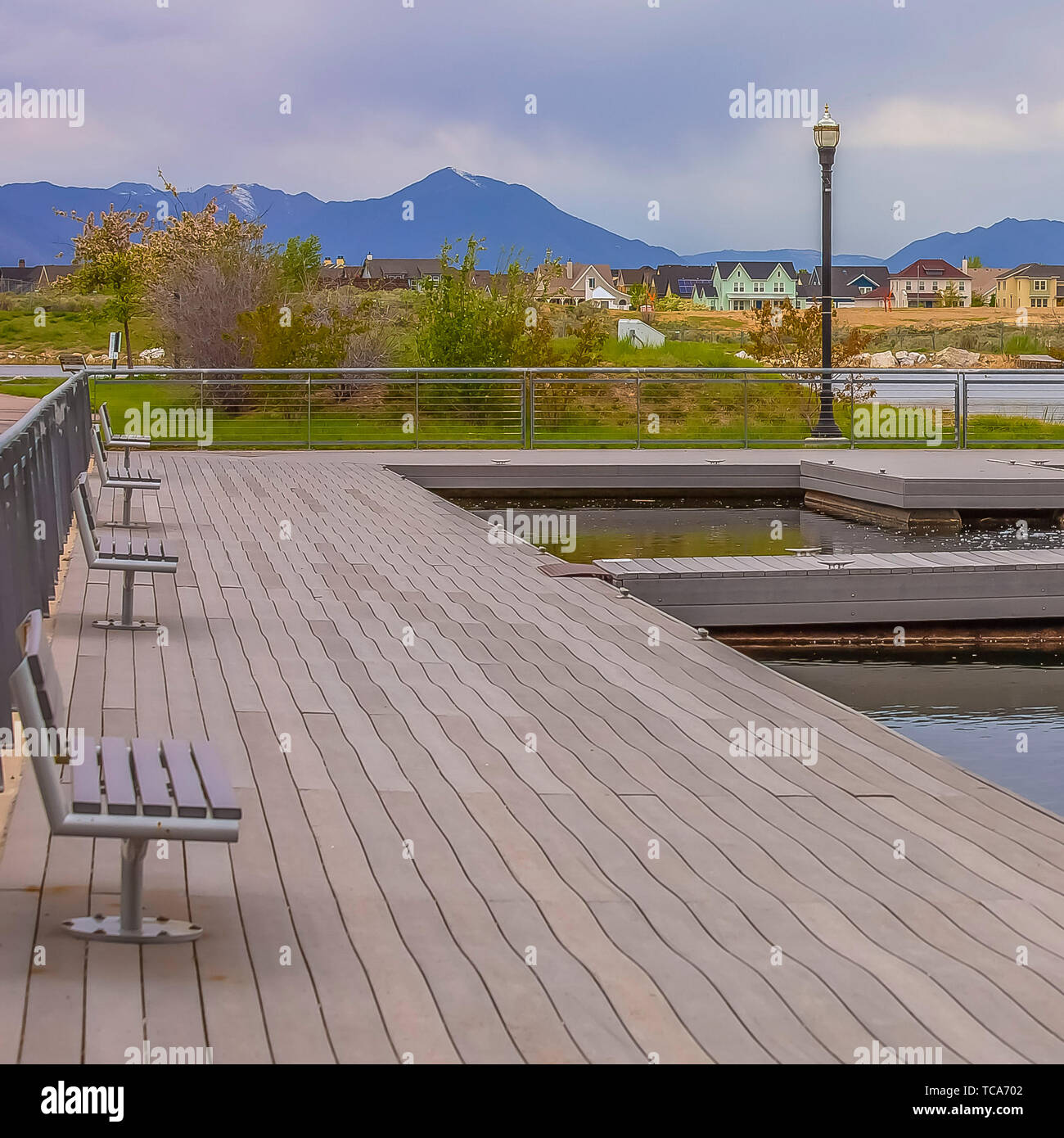 Square Lake with wooden deck and benches overlooking houses beyond the ...