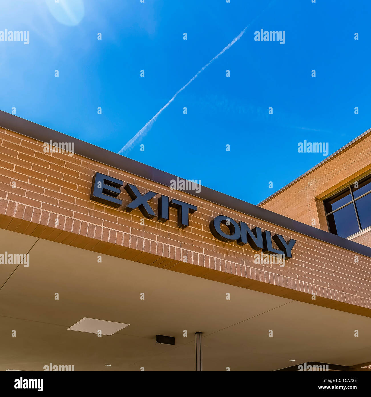 Square Exit Only sign on the exterior of a building against blue sky on ...
