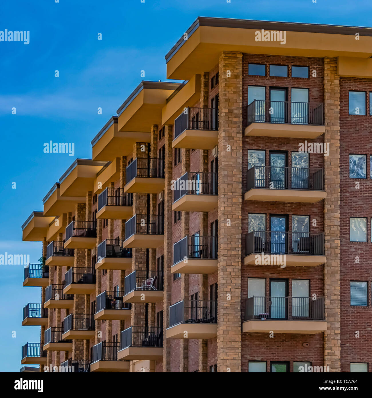 Square Residential brick building with balconies against blue sky with ...